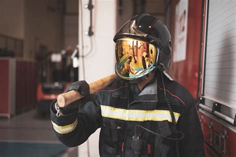 A Uniformed Firefighter Posing With An Ax Inside The Fire Station