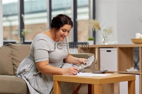 会计税收和人的概念 家里有钱文件和计算器的女人高清摄影大图 千库网