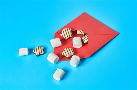 흩어져있는 과자 줄무늬 사탕 원통형 마시멜로가있는 빨간 종이 봉투가 파란색 책상 위에 놓여 있습니다 사랑 편지 개념입니다 클로즈업 갈색에 대한 스톡 사진 및 기타 이미지