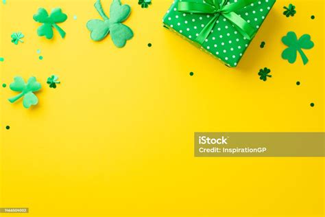 성 패트릭의 날 개념 빈 공간이 있는 격리된 노란색 배경에 리본 활 토끼풀과 세포일 모양의 색종이 조각이 있는 녹색 선물 상자의 상위 뷰 사진 3월에 대한 스톡 사진 및