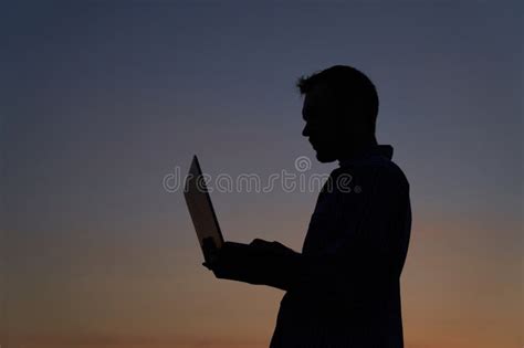 Male Programmer Of It Guy In Silhouette Using Laptop Outdoor At Sunset