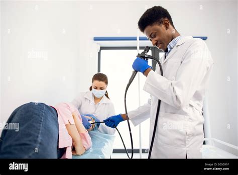 Young African American Man Doctor And Female Nurse Doing Endoscopy Procedure For Female Patient