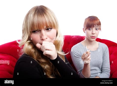 schöne junge blond und rot behaarte Mädchen auf dem roten Sofa Rauchen vor weißem Hintergrund