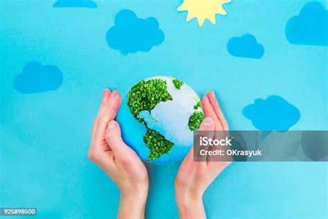 상위 뷰 여성 손 종이 태양과 구름과 파란 배경에 지구 종이 녹색 콩나물 합성 모델을 들고 당신의 손에 지구 행성 개념을 저장 텍스트를 위한 공간입니다 소유권 증서에 대한