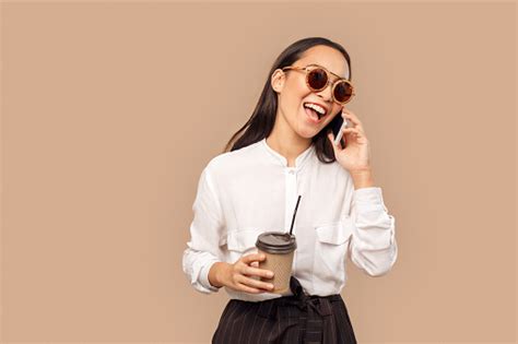 자유형 셔츠와 선글라스에 젊은 여자 서 고립 된 가방 과 커피 한 잔 이야기 에 전화 웃음 즐거운 갈색 머리에 대한 스톡 사진 및 기타 이미지 Istock