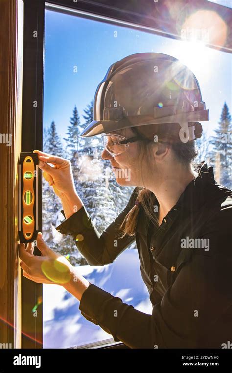 Worker Woman Uses A Spirit Level Instrument On Vertical Wooden Surface Next To A Window With