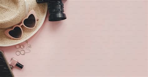 세련된 사진 카메라 선글라스 보석 밀짚 모자 가방 분홍색 종이에 화장품이 텍스트를위한 공간으로 놓여 있습니다