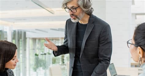 자신감 넘치는 성숙한 남성 경제학자가 테이블 옆에 서서 회의에서 젊은 여성 동료들에게 재무 데이터를 설명하고 있다 사진 Unsplash의 비즈니스 사람 이미지