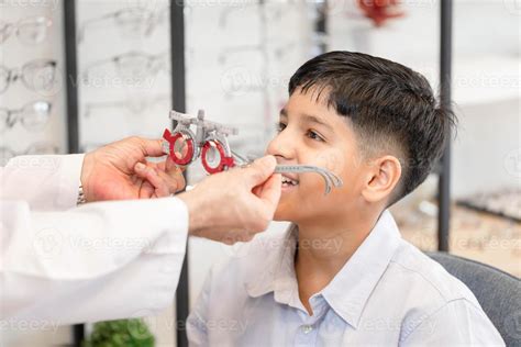 Cheerful Indian Thai Boy Choosing Glasses In Optics Store Boy Doing
