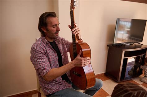 여가 시간에 따뜻한 조명 아래에서 실내에서 어쿠스틱 기타를 연주하는 남자 40 44세에 대한 스톡 사진 및 기타 이미지 40 44세 가구 가정 생활 Istock