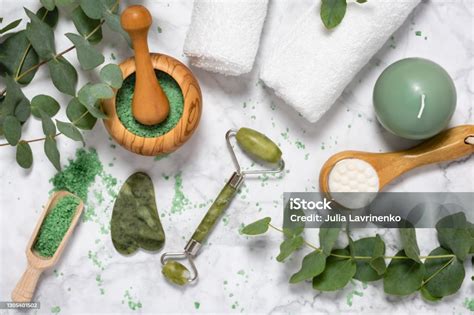 대리석 배경에 미용 옥 롤러 구아 샤 목욕 소금과 유칼립투스 가지를 가진 천연 웰빙 및 안티 에이징 스킨 케어 스파 페이스