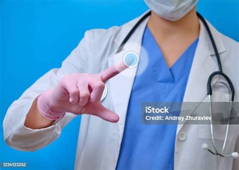 보호 장갑에 의사의 손은 가상 버튼 파란색 배경을 누릅니다 옆을 가리키는 손가락이 있는 흰색 실험실 코트를 입은 간호사 복사