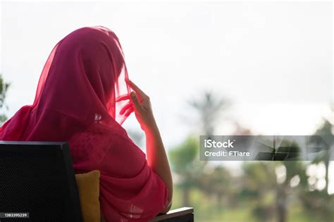 이슬람교도 붉은 머리 스카프를 입은 아랍 여성 테라스의 안락의자에 앉아 아랍 에미리트의 일몰 야자수 해변을 바라보는 히잡의 실루엣 35 39세에 대한 스톡 사진 및 기타