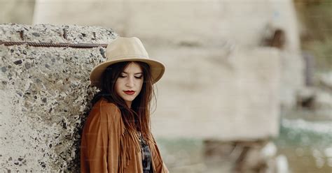 모자 가죽 가방 프린지 판초와 부츠를 가진 아름다운 세련된 보헤미안 여자 집시 히피의 소녀는 산의 강 바위 근처에서 포즈를 취하는 젊은 여행자처럼 보입니다 관능적 인