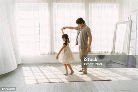 집에서 왈츠를 추는 아름다운 치마를 입은 아시아 아버지와 어린 딸의 초상화 행복한 중국인 또는 일본인 아버지는 귀여운 딸과 함께 자유 시간을 보내고 거실에서 주말을 함께