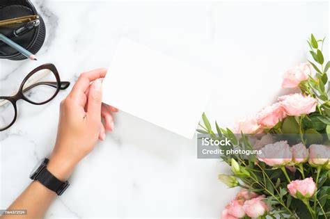 문구 장미 꽃 다발 안경 플랫 레이 상단보기와 현대 홈 오피스 책상 작업 공간을 통해 빈 종이 카드 모형을 들고 여자 손 손에