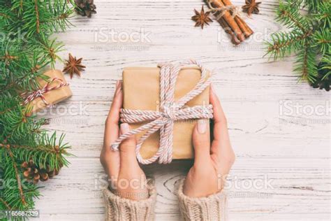 흰색 나무 테이블 배경에 재활용 종이에 수제 선물 상자를 들고 여성의 손 크리스마스 준비 개념 선물 포장 배경 격 조 12월에