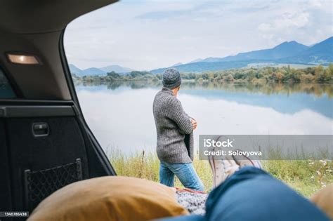 따뜻한 니트 옷과 청바지를 입고 산호수 전망을 즐기는 남자에 흰색 운동화를 입은 여성 다리로 자동차 트렁크 보기 아늑한 초가을 커플 자동차 여행 개념 이미지 운전하기에 대한