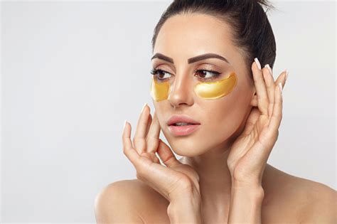 회색 배경에 눈을 위한 금색 패치를 가진 아름다운 여자 눈 밑에 패치 콜라겐 마스크 20 24세에 대한 스톡 사진 및 기타