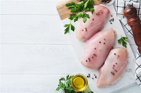 닭가슴살 하얀 나무 테이블 배경에 흰 돌 커팅 보드에 향신료 올리브 오일 및 파슬리가있는 두 개의 치킨 필레 복사 공간이 있는 위쪽 보기입니다 음식 고기 요리 배경 0명에