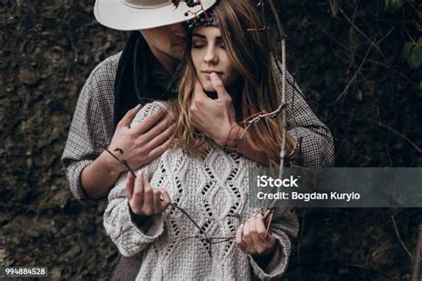 Hipster 세련 된 커플 포옹입니다 Boho 집시 여자 그녀의 입술을 수용 하는 모자에 분기 및 남자를 잡고 대기 관능적인 순간입니다 소박한 세련 된 보세요입니다 2명에