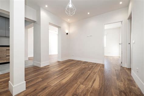 개방형 주방이 있는 거실과 짙은 색 나무 바닥과 갓 칠한 벽이 있는 여러 방으로 통하는 출입구가 있습니다 프리미엄 사진