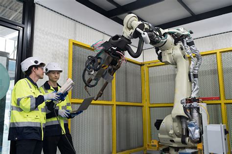 두 명의 남성 엔지니어가 건물 방 작업장에서 자동 로봇 손 기계를 제어합니다 제어 자동 로봇 팔 시스템으로 작업하는 남성 기술자 작업자 25 29세에 대한 스톡 사진 및