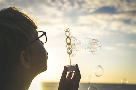 젊은 금발의 소년은 필드에 거품의 긴 문자열을 불면 앞에 귀여운 아이는 비누 끓는 바다 빈티지 톤에 등급 아름 다운 화창한 오후 이미지에서 야외에서 노는 좋은 아이 건강한