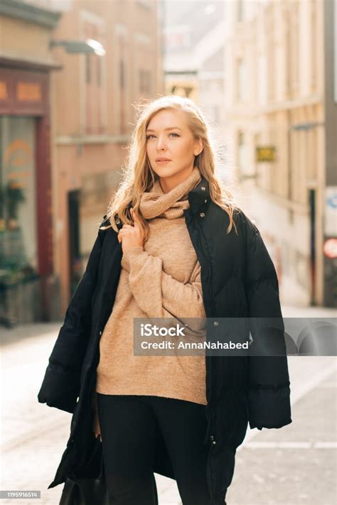 베이지 색 롤 넥 풀오버와 블랙 패딩 코트를 입은 젊은 아름다운 여성의 스트리트 패션 초상화 거리에 대한 스톡 사진 및 기타 이미지 Istock