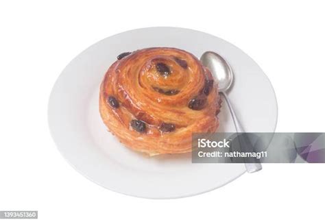 나선형 덴마크 패스트리 또는 하얀 접시 위에 건포도가 든 달콤한 롤빵과 작은 찻 숟가락이 흰색 배경에 고립 된 아침 식사를 제공합니다 0명에 대한 스톡 사진 및 기타 이미지