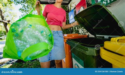 A Young Beautiful Girl Throws Sorted Garbage Into Special Bins Stock