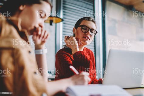 젊은 관심 힙스터 소녀 안경에 그녀의 여성 친구를 만드는 계획을 찾고 캠퍼스에서 동료와 노트북 장치와 시간을 보내는 영리한 백인