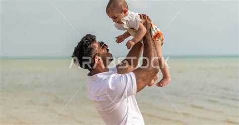 صورة مقربة لأب عربي خليجي سعودي يرتدي النظاراة الشمسية ويحمل إبنته بحب
