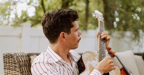 고리버들 의자에 앉아 기타를 연주하는 남자 사진 Unsplash의 음악가 이미지