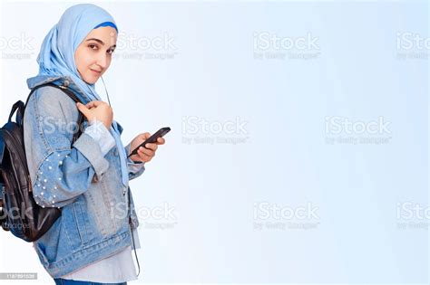 현대 무슬림 학생 소녀는 스마트 폰에서 음악 팟 캐스트 및 오디오 북을 듣습니다 헤드폰으로 히잡 듣기 노래에 행복한 무슬림 여자 라디오에 대한 스톡 사진 및 기타 이미지