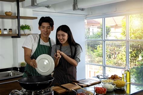 현대 부엌에서 샐러드의 성분으로 장식 된 요리 아침 식사를 준비 하는 쾌활 한 액션 홀딩 플레이트에 앞치마 귀여운 행복 커플의 초상화와 좋은 시간을 보내고 가정 생활에 대한