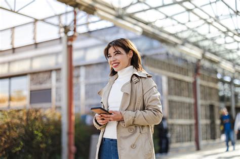 기차역에서 휴대 전화를 사용 하 고 웃고 있는 젊은 여자의 초상화 30 34세에 대한 스톡 사진 및 기타 이미지 30 34세 Brand Name Smart Phone