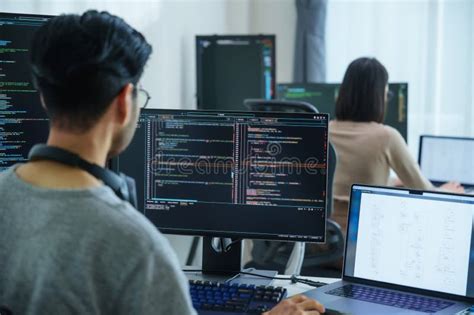Asian Software Developers Working On Multiple Screens Displaying Code