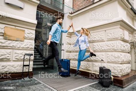 젊은 쾌활한 부부는 호텔에 도착하기 전에 여행 가방 점프와 다섯을주는 재미를 야외에서 즐거운 시간을 보내는 커플 구시 가지 건물 근처 관광객에 대한 스톡 사진 및 기타