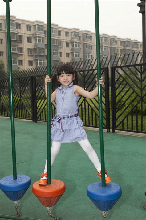 东方人 婴儿 儿童 一个人 攀登 竖图 彩色 室外 白天 正面 快乐 幸福 纯洁 北京 中国 图片 小孩 小女孩 娱乐设施 滑梯 放松 可爱