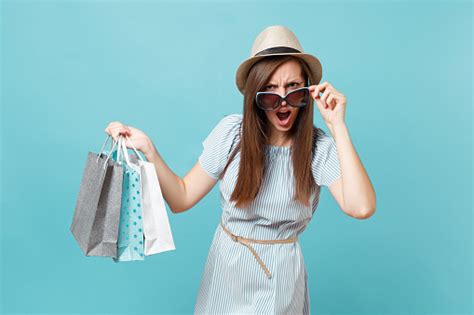 세로 여름 드레스 밀 짚 모자 블루 파스텔 배경에 고립 쇼핑 후 구매와 패키지 가방을 들고 선글라스 유행 매력적인 행복 한 여자 광고에 대 한 공간을 복사 합니다 가방에