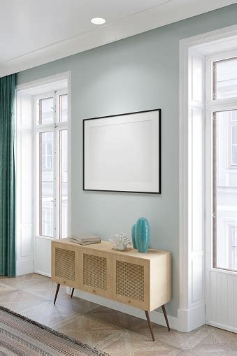 두 발코니 문 사이의 연한 파란색 벽에 조명 된 수평 포스터가있는 방 등나무 문이있는 나무 사이드 보드의 장식 녹색 커튼 및 쪽모이 세공 마루 바닥의 카펫 사이드보드에 대한