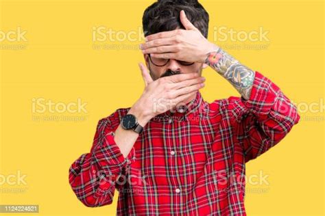 격리 된 배경 덮 음 눈과 손으로 입을 통해 안경을 쓰고 잘생긴 젊은이 놀라게 하 고 충격 감정 숨기기 가리기에 대한 스톡 사진