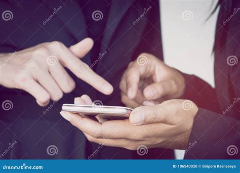 Two Business Woman Looking At Mobile Phone Talking About Their Project