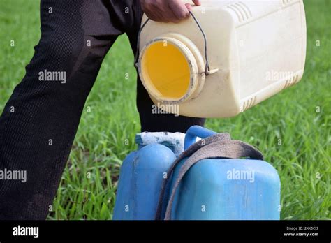 A Man Farmer Pouring Herbicides And Chemical Into Container In Green Field Foam Is Coming Out