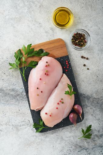 닭가슴살 회색 돌 테이블 배경에 검은 돌 커팅 보드에 향신료 올리브 오일 및 파슬리가있는 두 개의 치킨 필레 복사 공간이 있는 위쪽 보기입니다 음식 고기 요리 배경 0명에