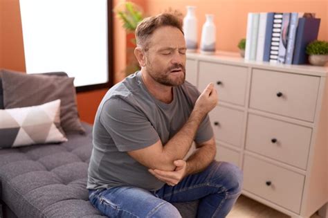 Homem De Meia Idade Sentado No Sof Sofrendo De Dor De Cotovelo Em Casa Foto Premium