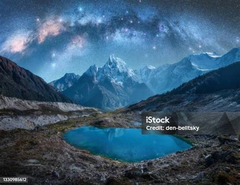 밤에 눈 덮인 산과 호수 위에 은하수 눈이 쌓인 풍경은 높은 바위 별이 빛나는 하늘 네팔의 물 반사를 덮고 있습니다 별과 하늘 히말라야의 밝은 은하수 공간과 자연 은하수에
