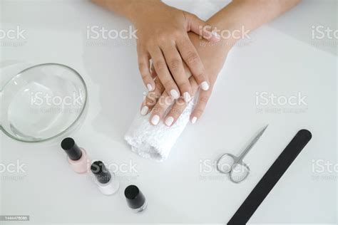 흰색 매니큐어로 깔끔한 여성의 손이 수건 롤러에 누워 있고 매니큐어 액세서리가 옆 테이블에 놓여 있습니다 손 클로즈업 가린 얼굴에 대한 스톡 사진 및 기타 이미지 Istock
