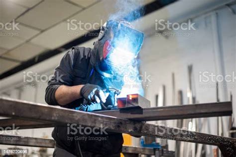 보호 마스크와 작업복을 입고 용접공으로 일하는 남자가 Migmag 용접기로 작업을 수행합니다 공장에서 용접 작업을 생산합니다 1940 1949 년에 대한 스톡 사진 및 기타